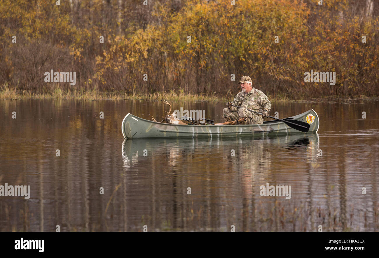 Crossbow hunter returning in a canoe with his 8-point white-tailed buck ...