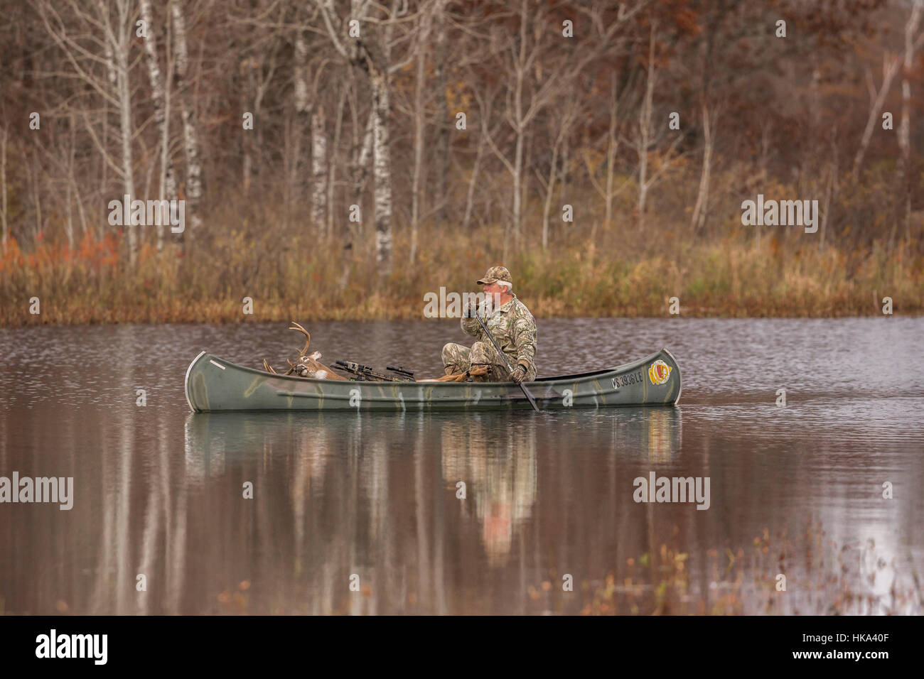 Crossbow hunter returning in a canoe with his 8-point white-tailed buck ...