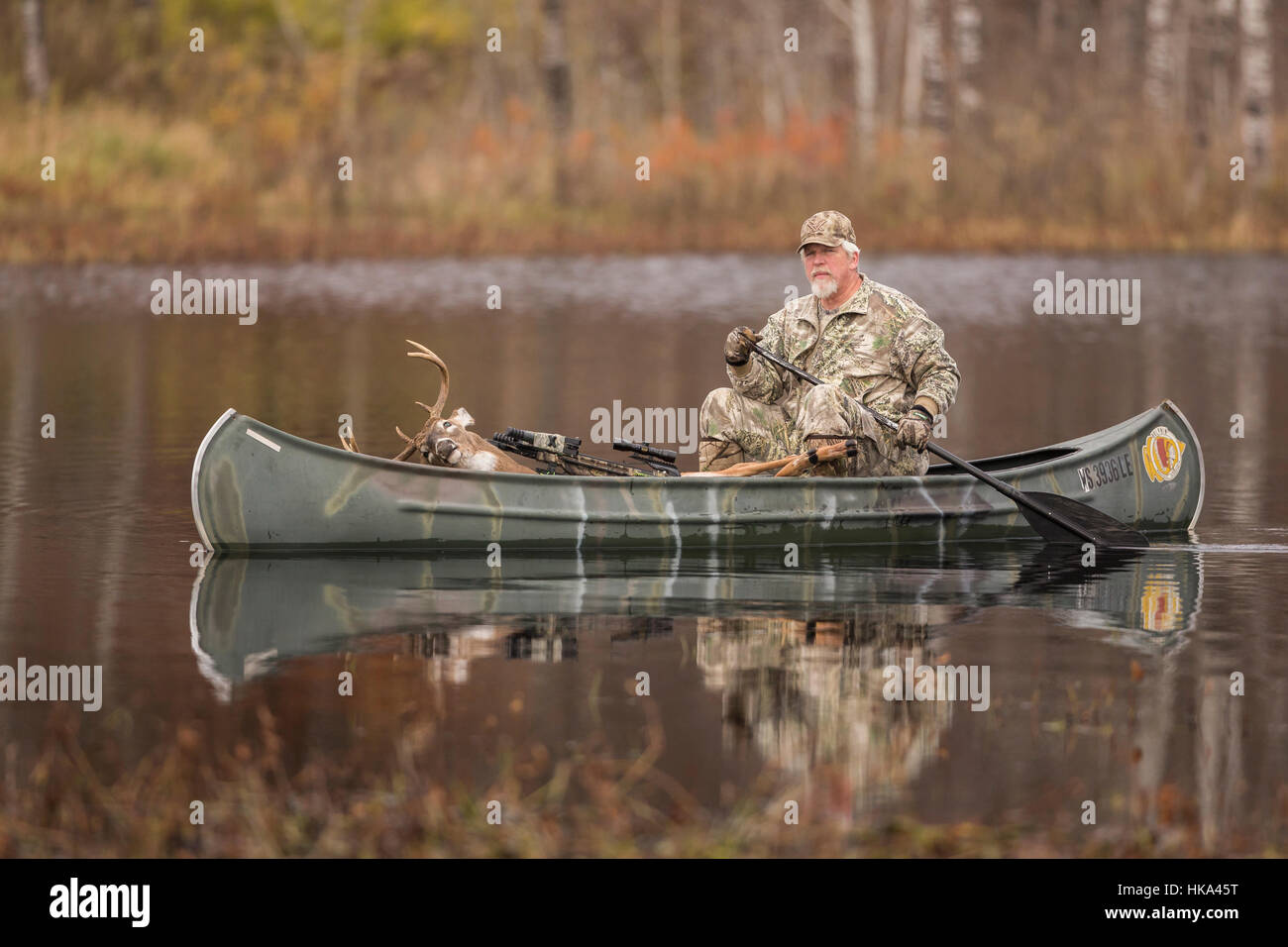 Crossbow hunter returning in a canoe with his 8-point white-tailed buck ...