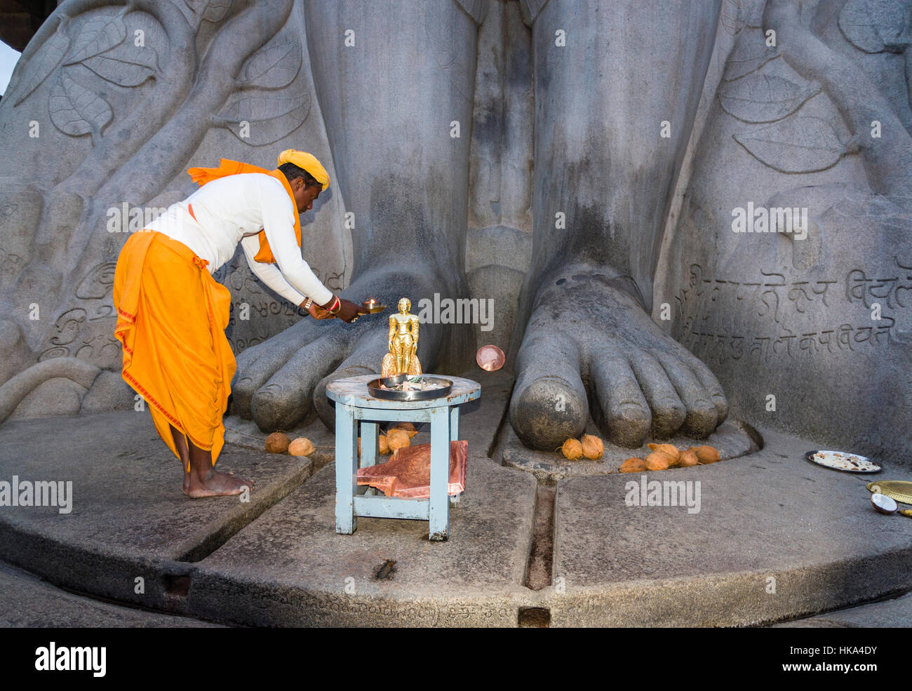 A local priest is praying at the feet of Gomateshwara, the statue of ...