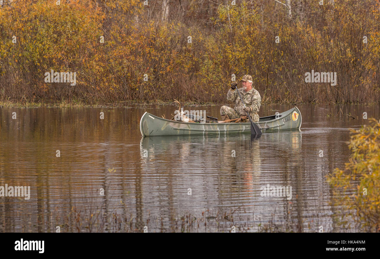 Crossbow hunter returning in a canoe with his 8-point white-tailed buck ...