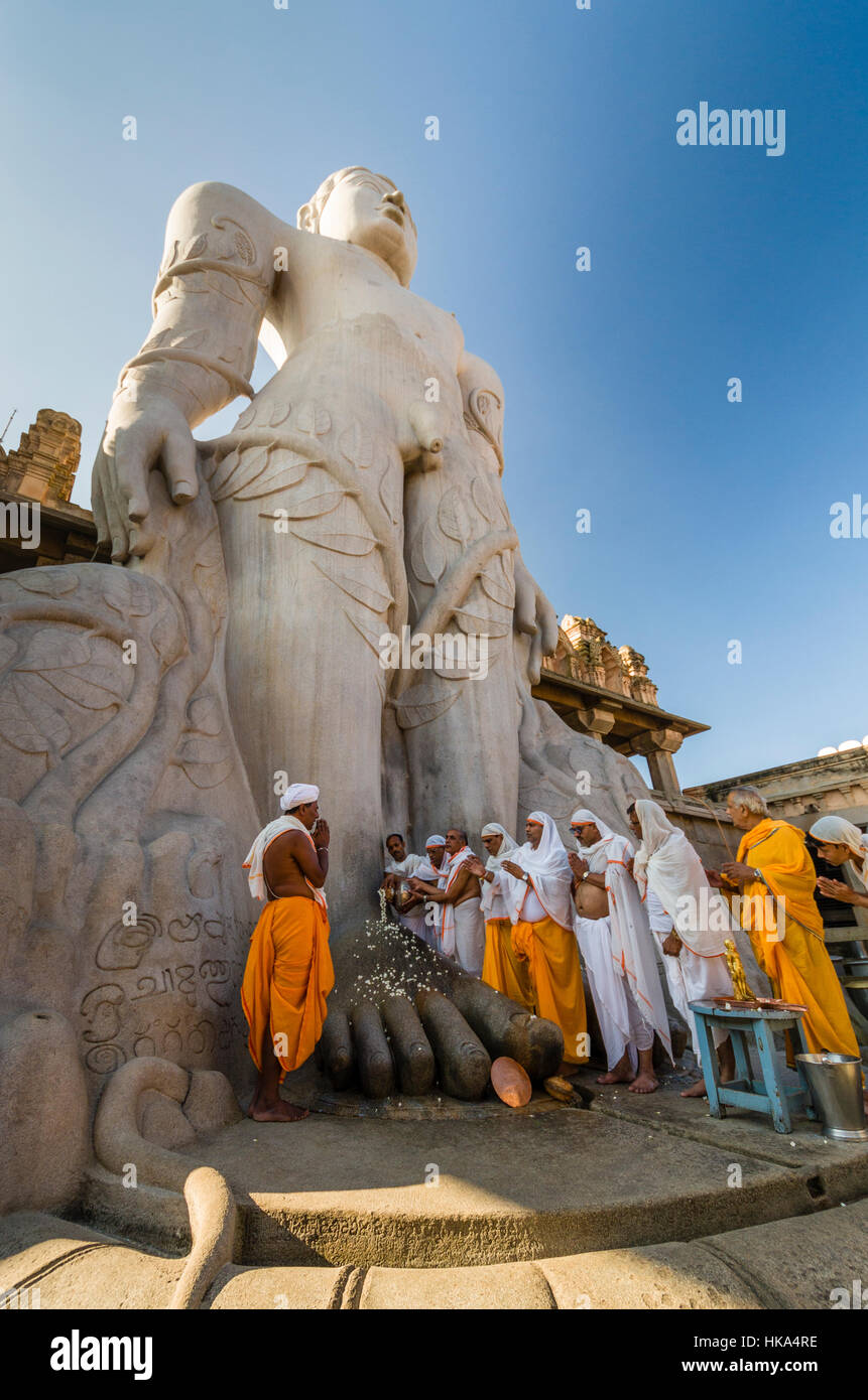 A group of Jain pilgrims is praying at the feet of Gomateshwara, the ...