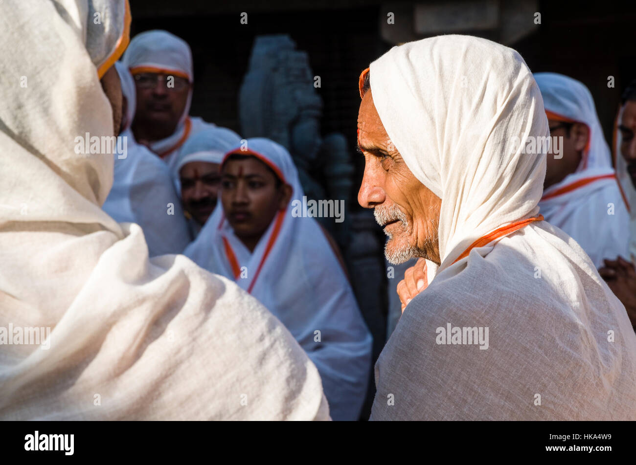 A group of Jain pilgrims is reciting religious texts at the feet of ...