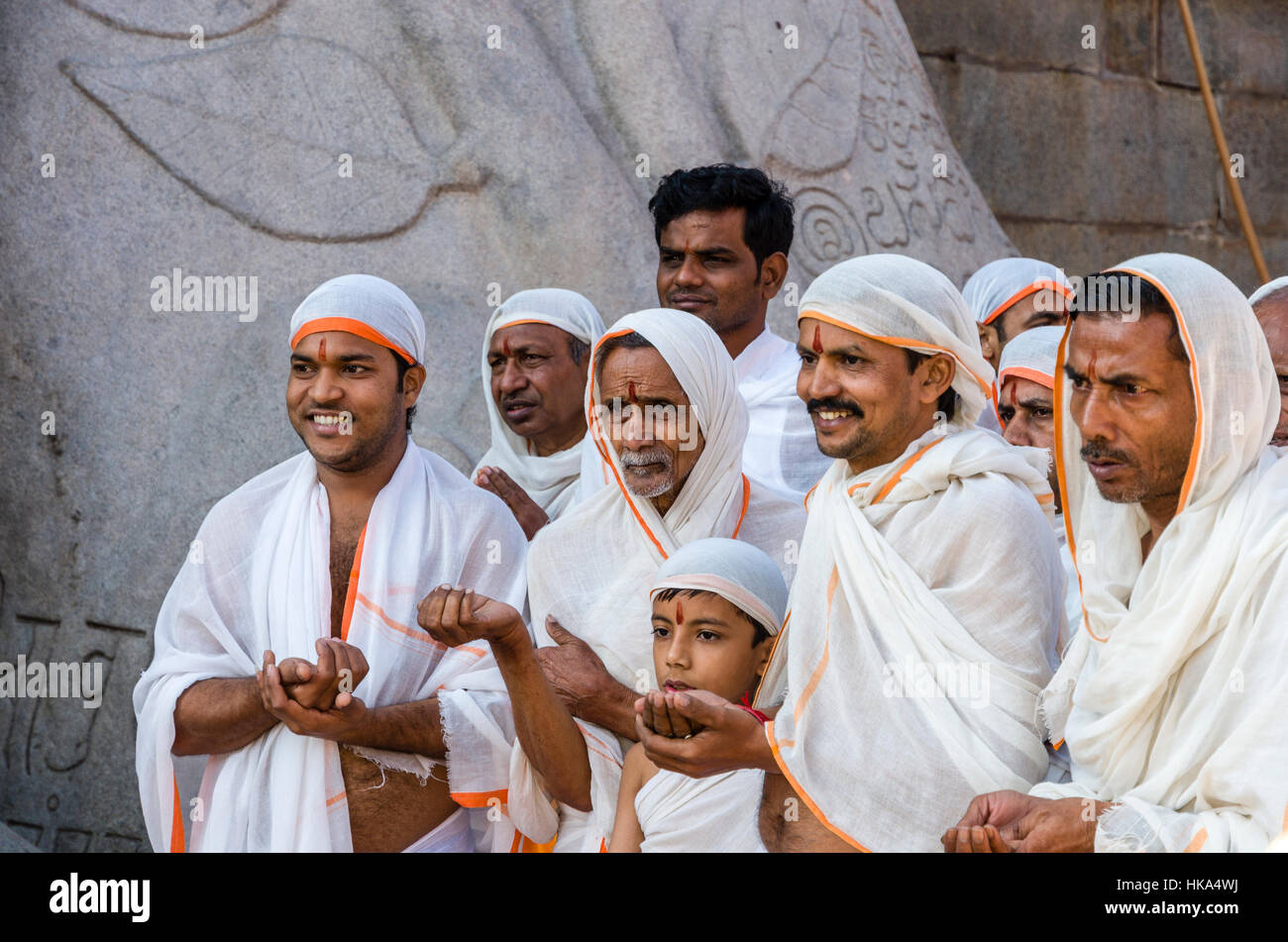 A group of Jain pilgrims is reciting religious texts at the feet of ...