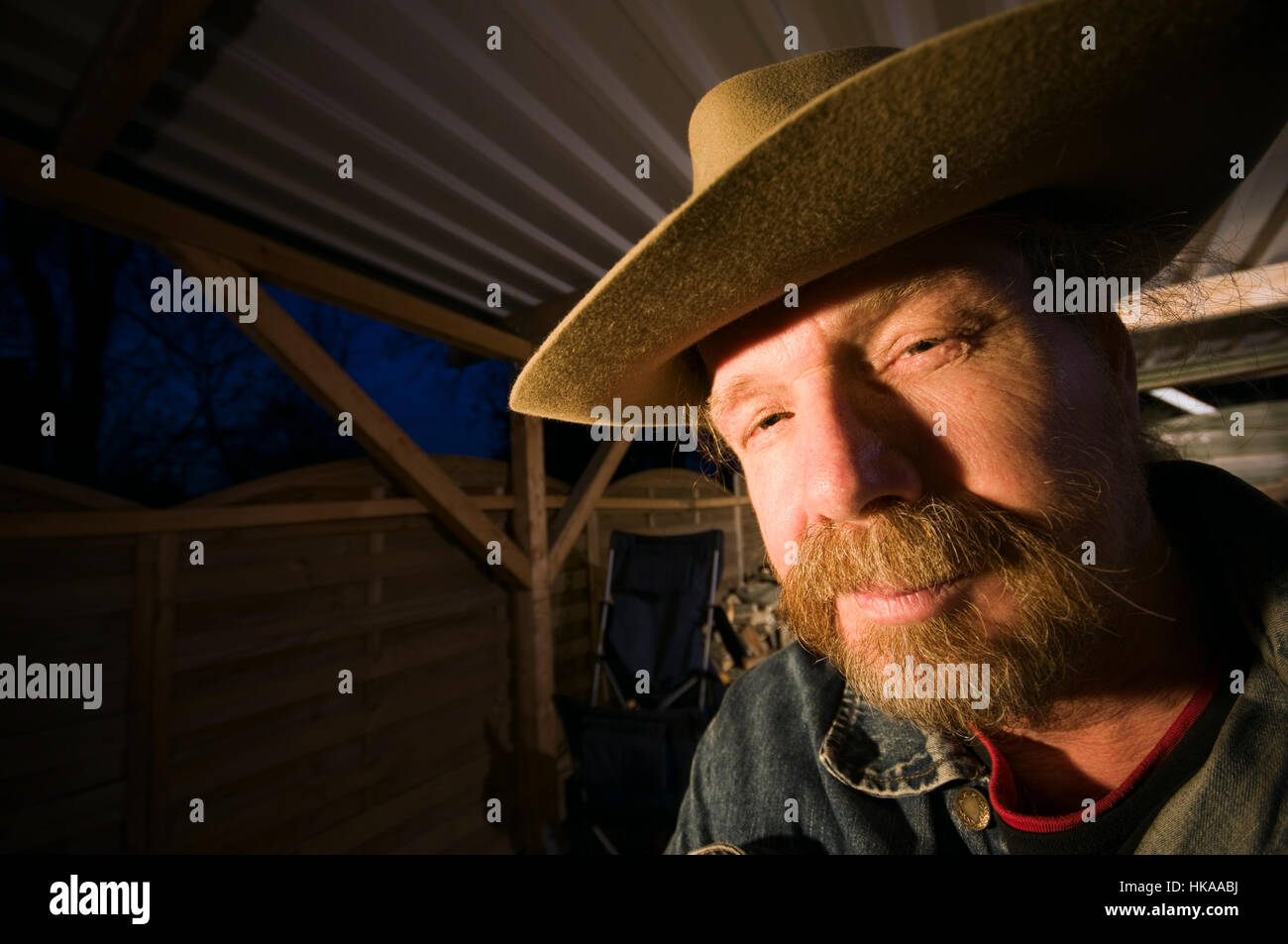 Wide-angled portrait of an older man with a full beard in a barn at ...