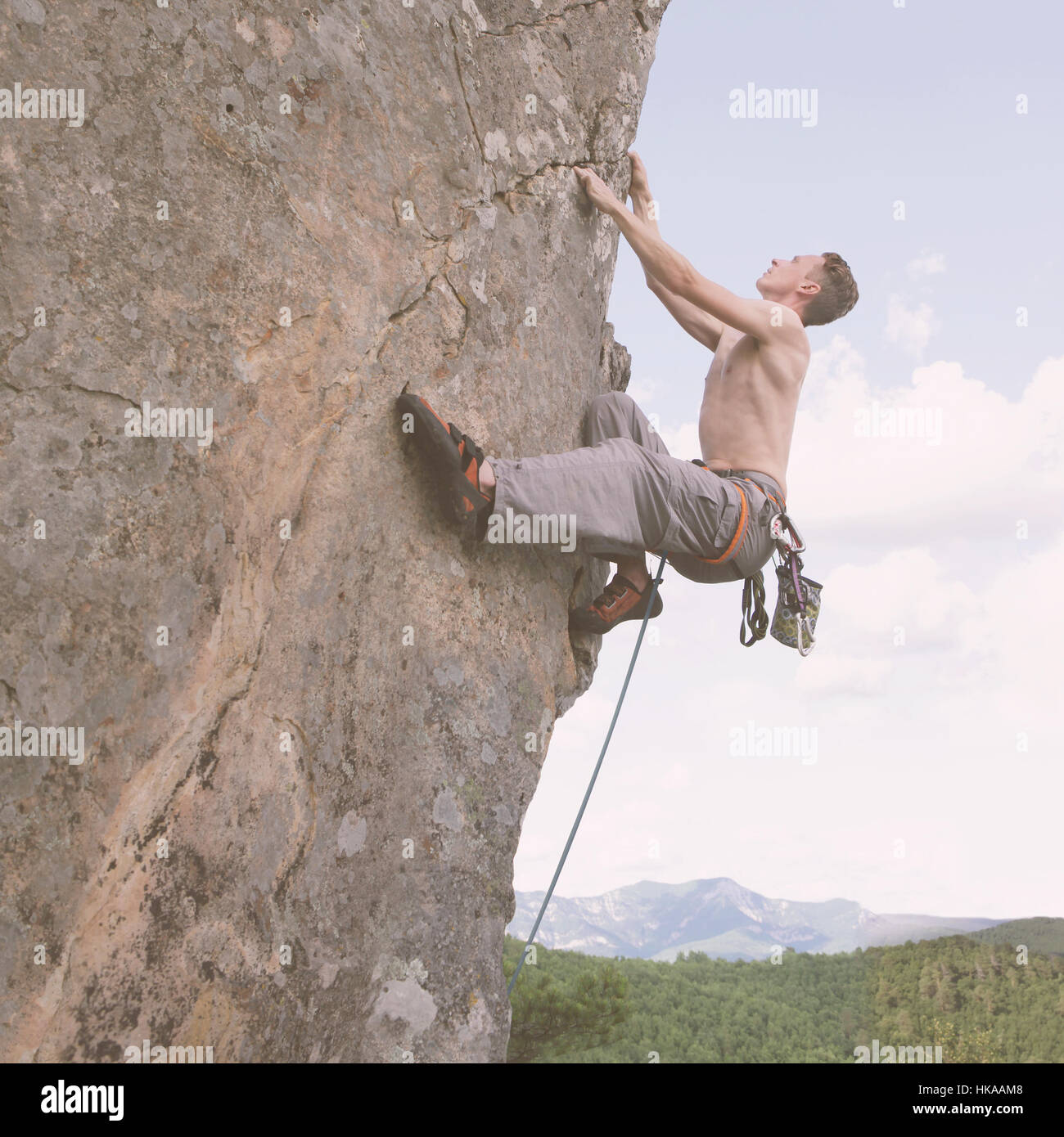 Young man climbing on rock. Toned Image Stock Photo - Alamy