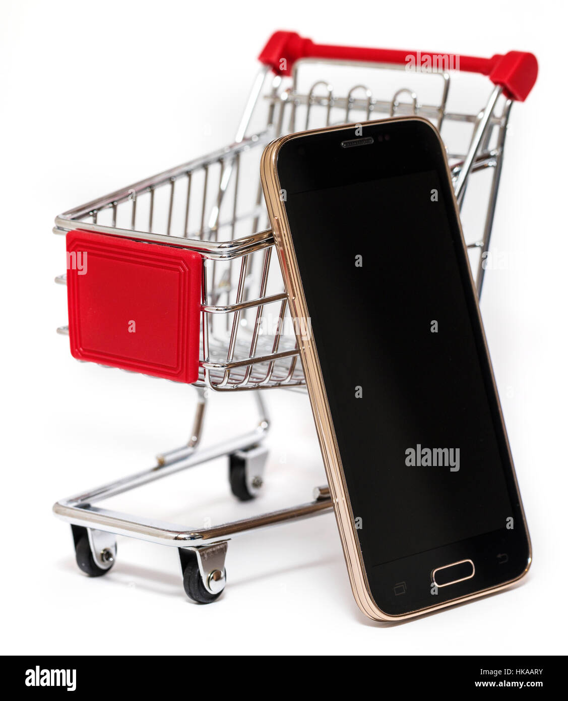Shopping cart with black and gold smart phone isolated on white ...