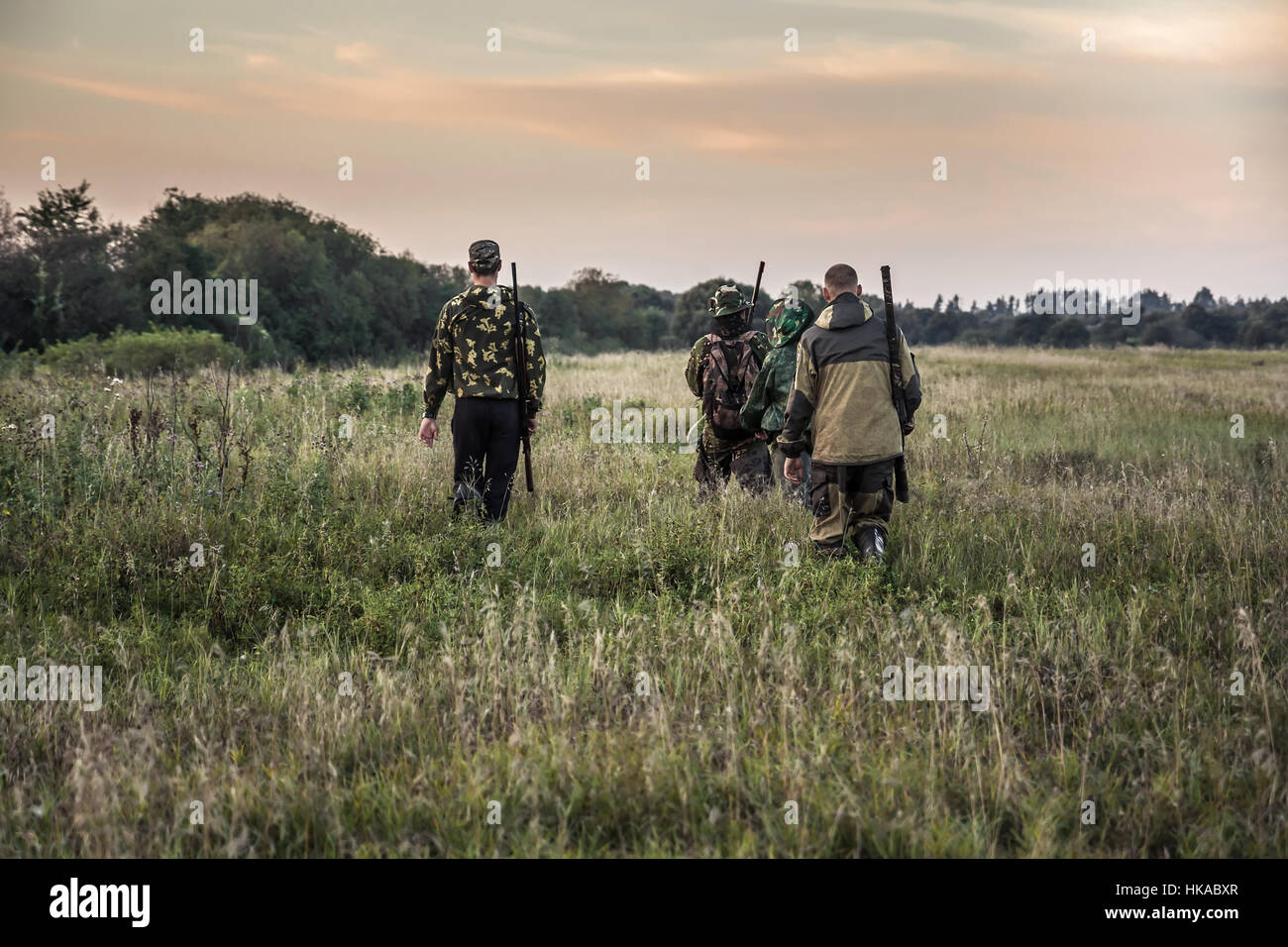 Hunting scene with hunters going through rural field during hunting ...
