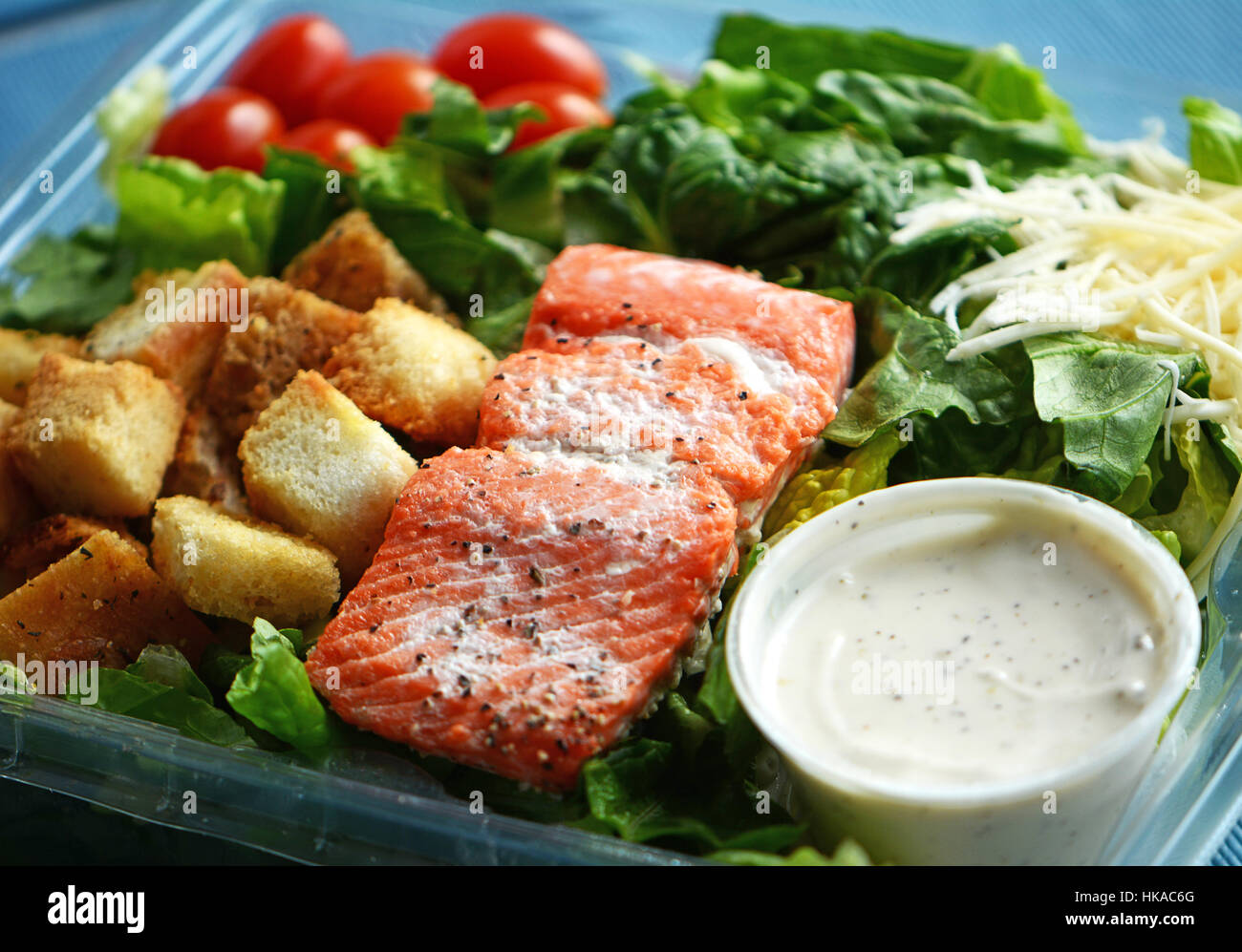 Cold cooked salmon filet with assorted salad ingredients in plastic box ...
