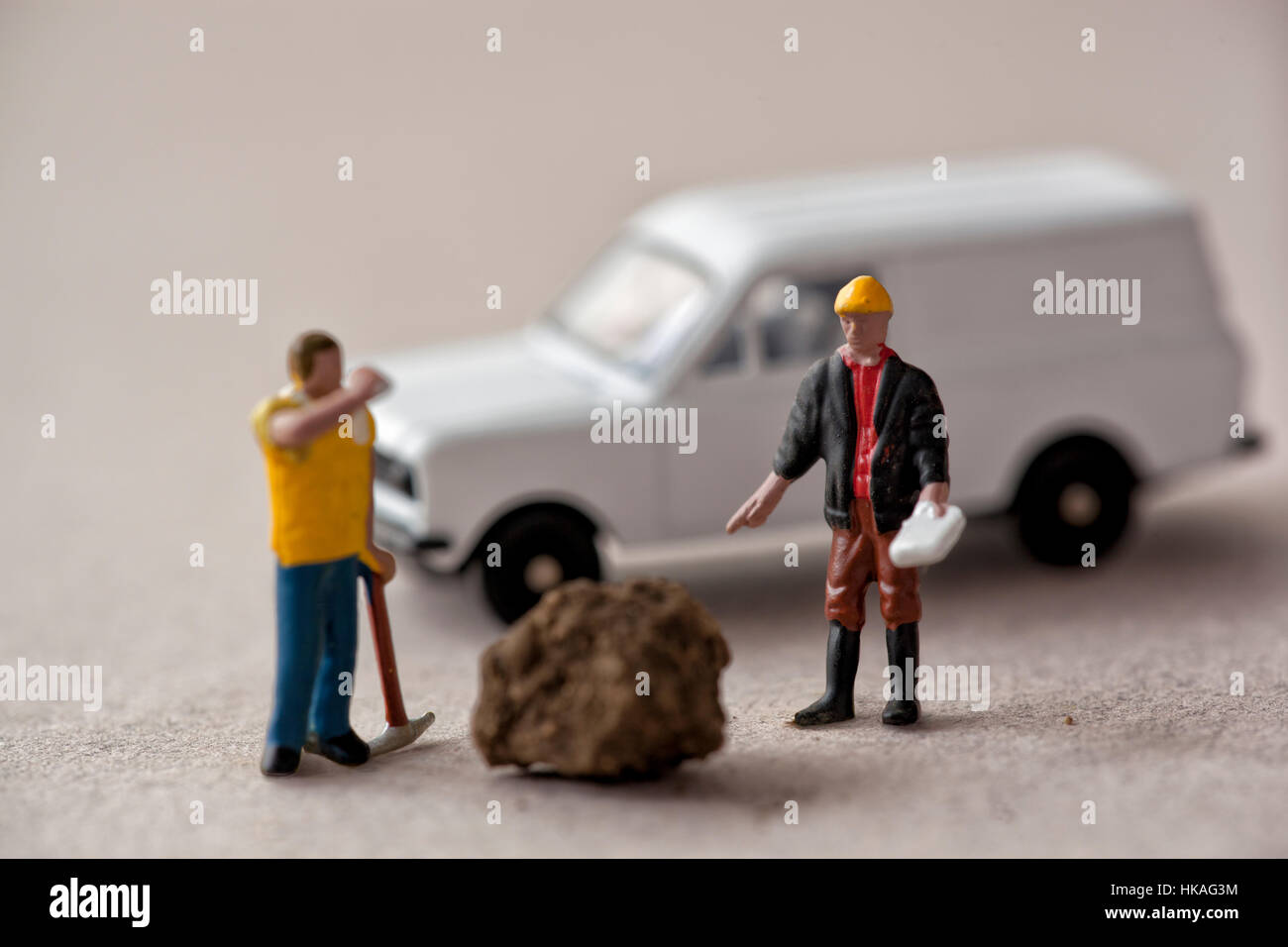 Miniature model supervisor and workman with a lump of earth and white ...