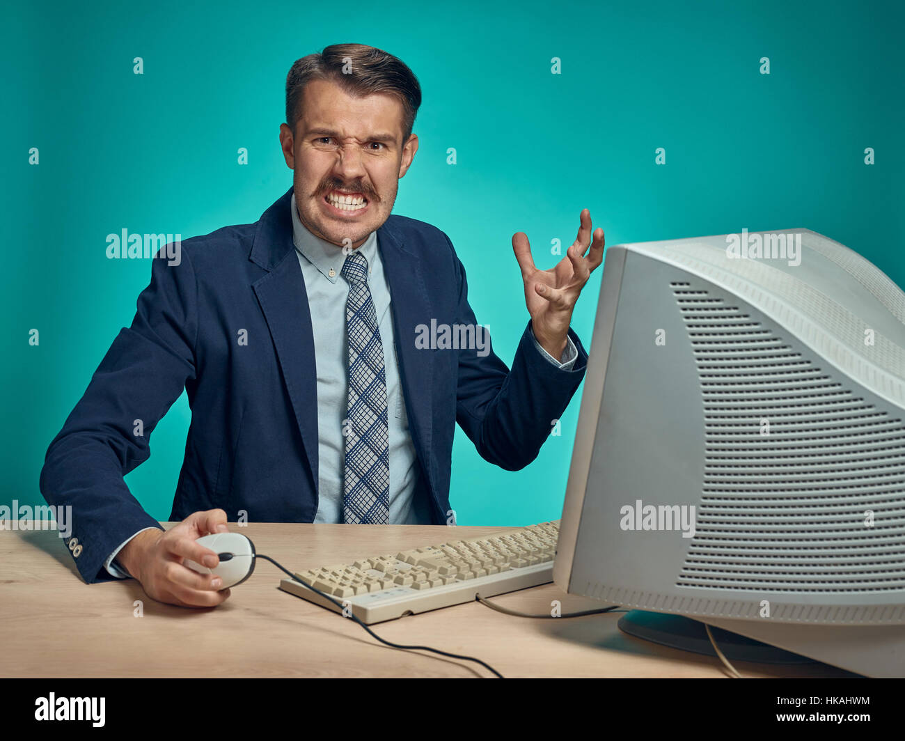 Angry businessman using a monitor against blue background Stock Photo ...