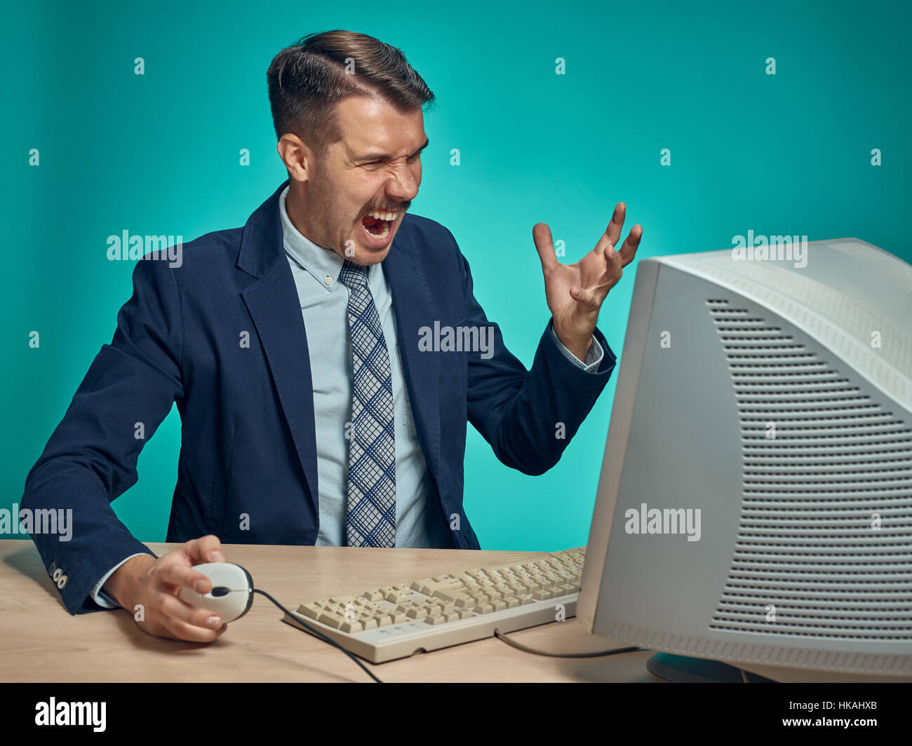 Angry businessman using a monitor against blue background Stock Photo ...