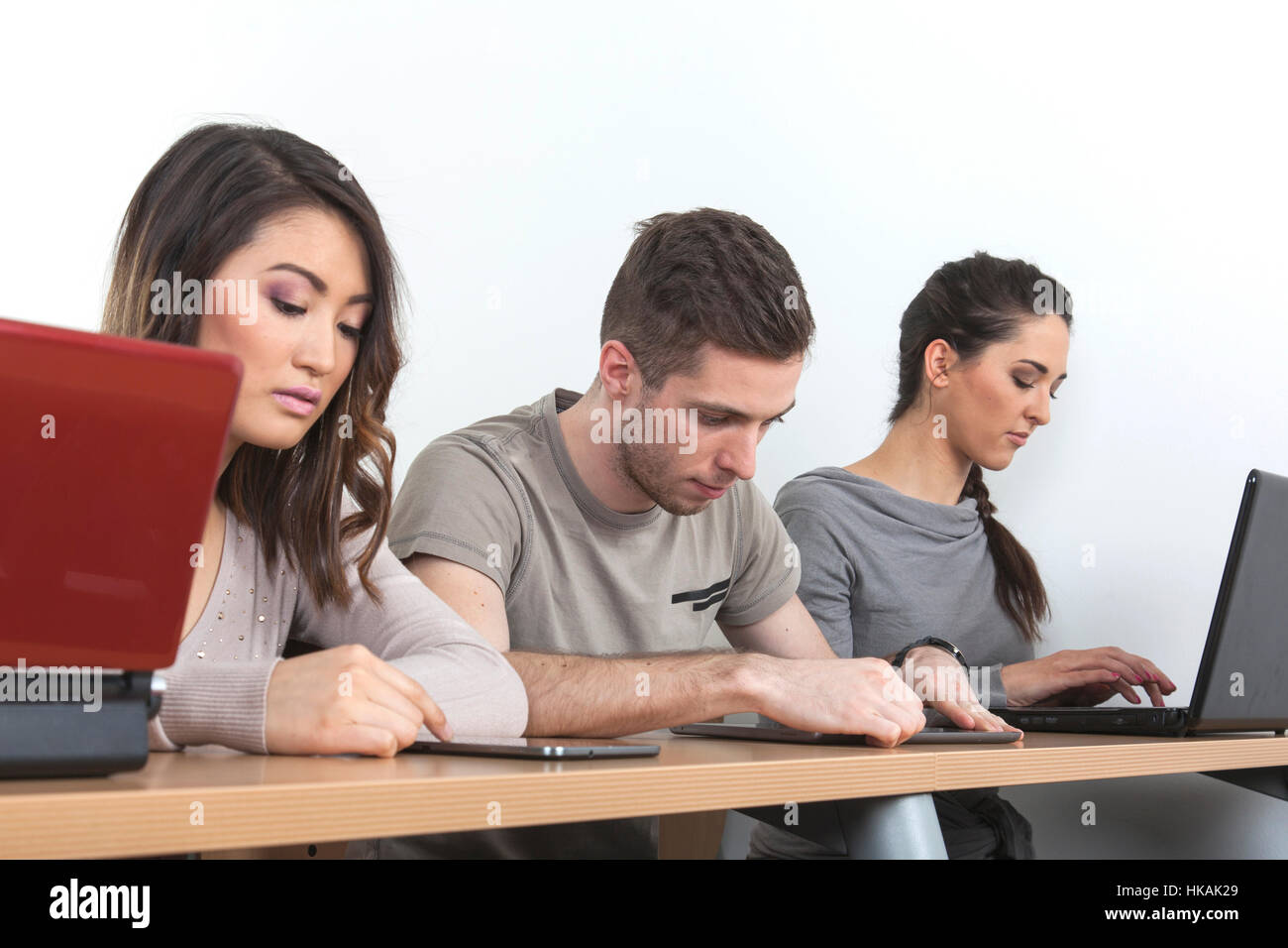 Three students learning with laptops and tablets Stock Photo - Alamy