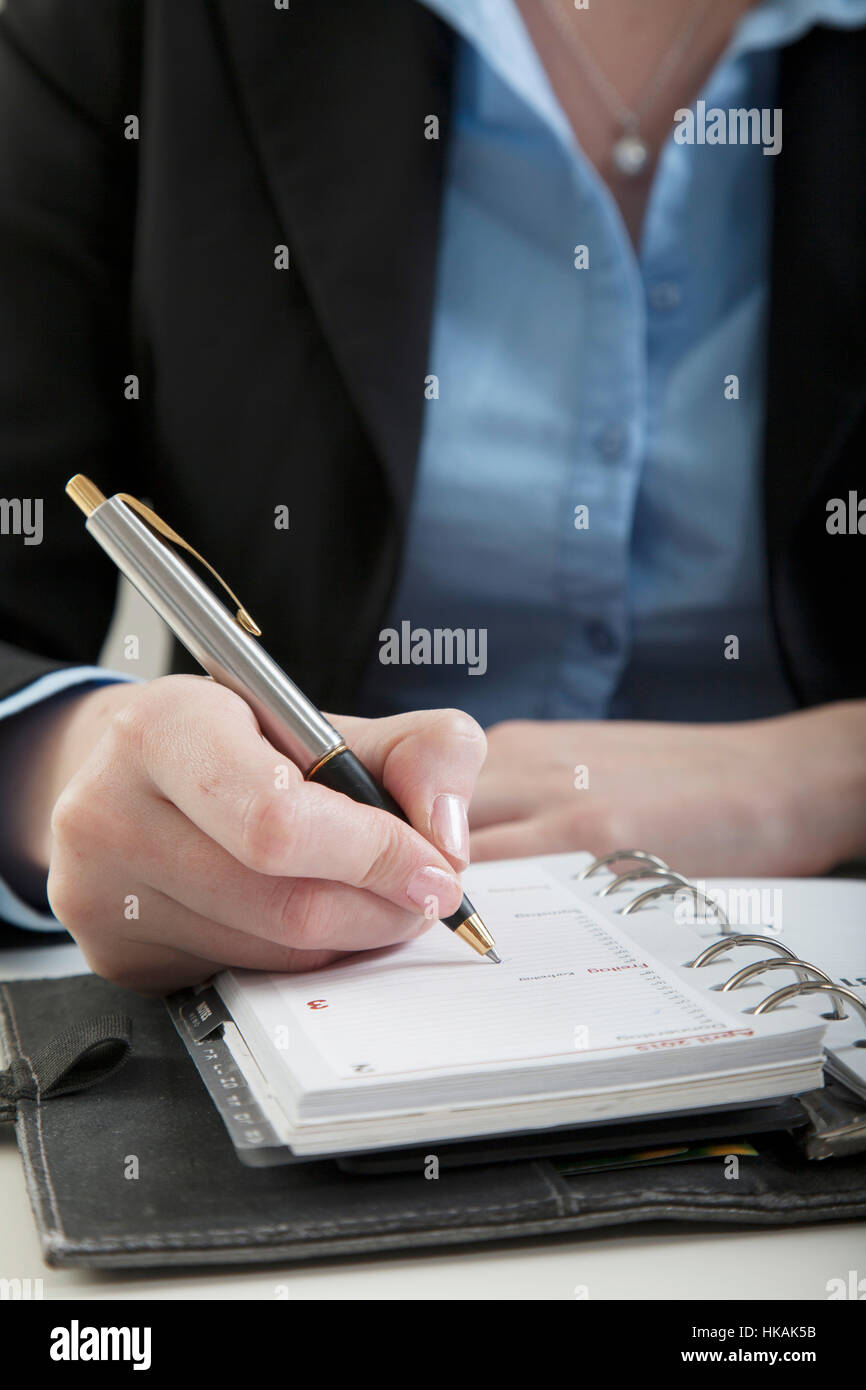 secretary writes down an entry into the calendar of her diary Stock ...