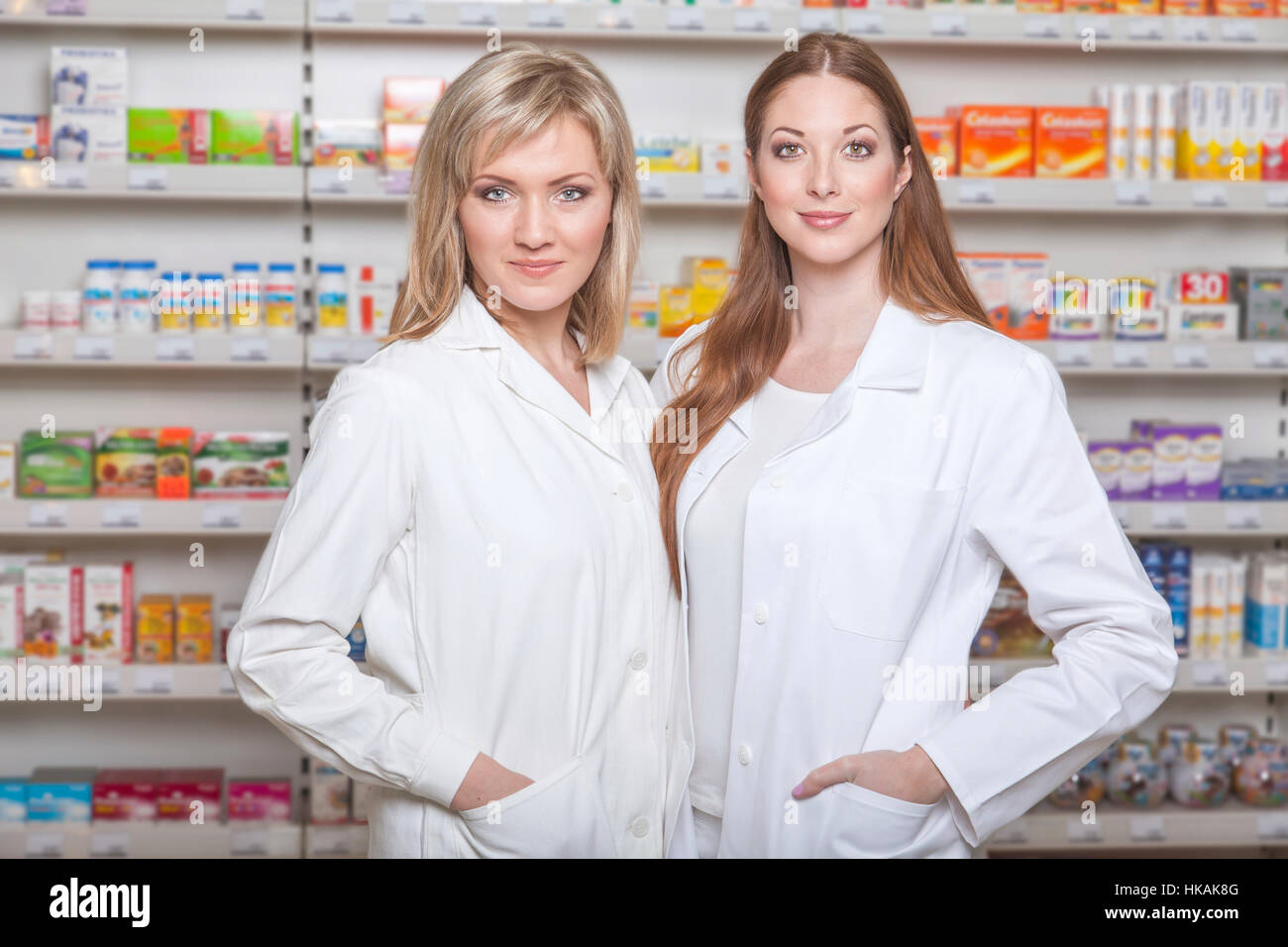 Two determined female pharmacists with coats in pharmacy environment ...