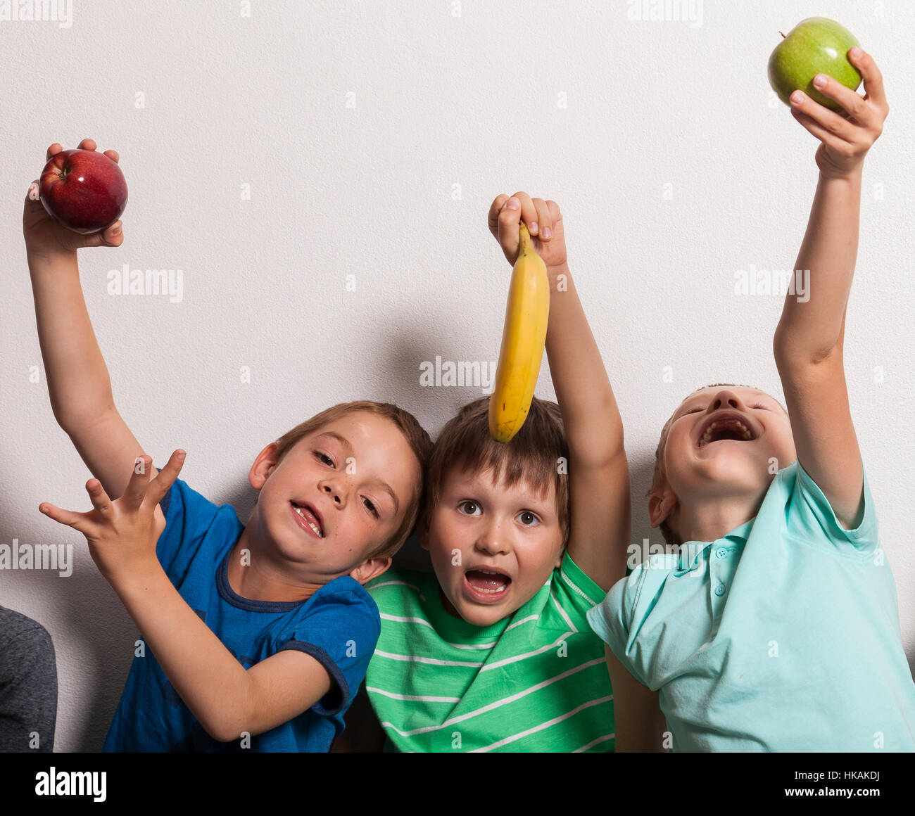 Three silly primary school kids playing with apples and banana Stock ...