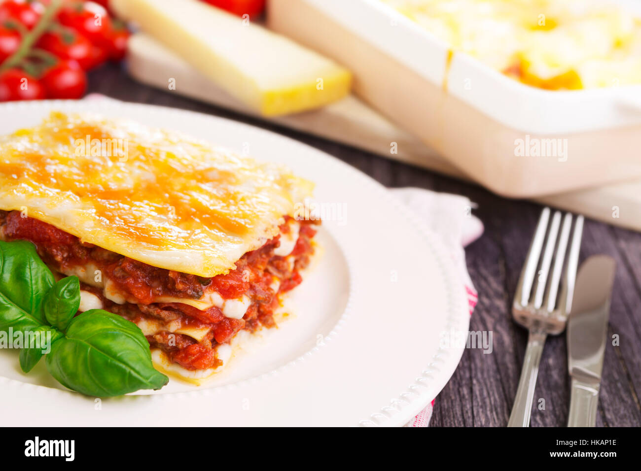 A portion of homemade lasagna on a plate on a brightly lit table Stock ...