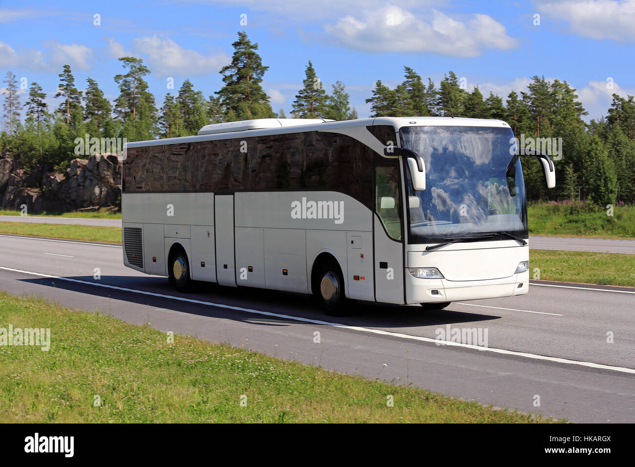 New white coach bus moves along freeway through beautiful scenery on a ...