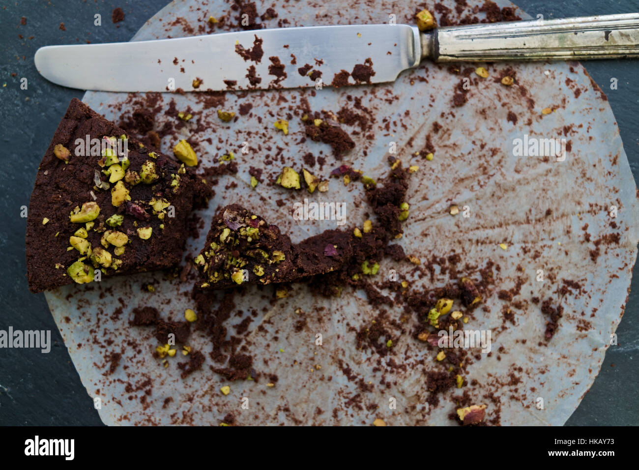 Crumbling last piece of dark chocolate and pistachio cake with rustic ...