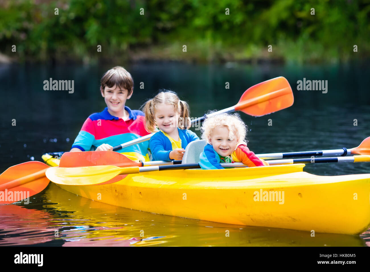 Happy family with two kids enjoying kayak ride on beautiful river ...
