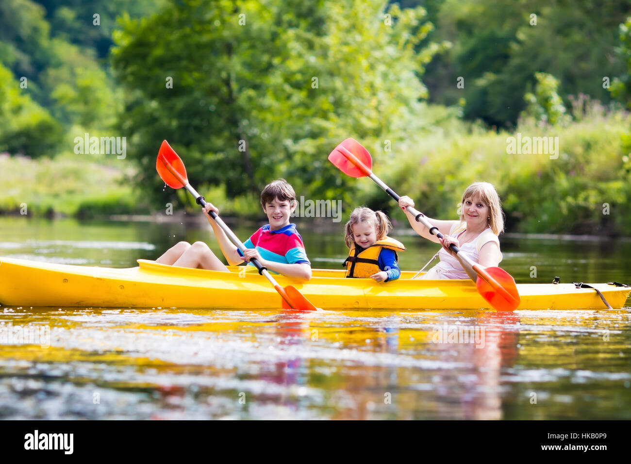 Happy family with two kids enjoying kayak ride on beautiful river ...
