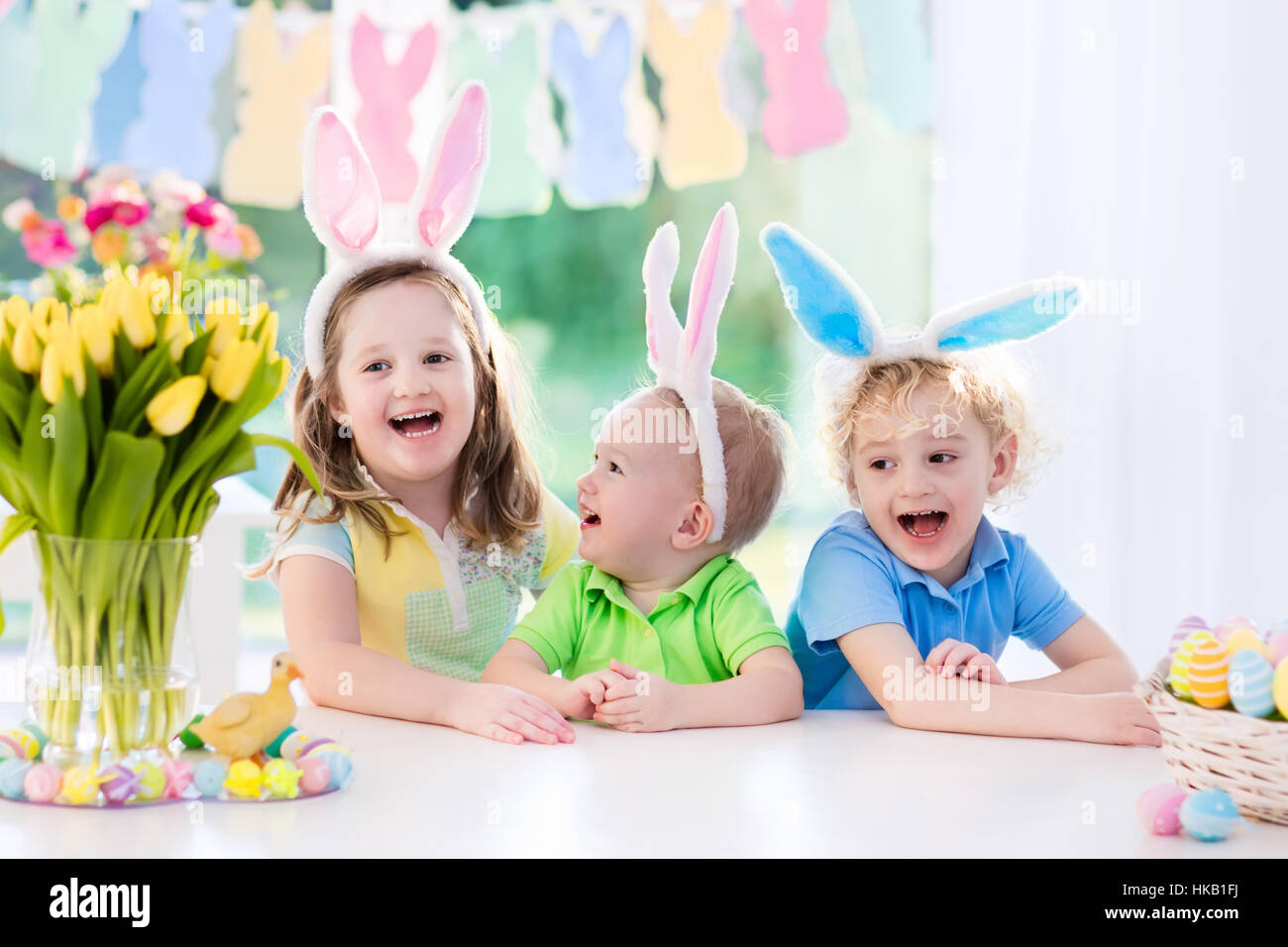 Boy and girl in bunny ears at breakfast on Easter morning at table with ...