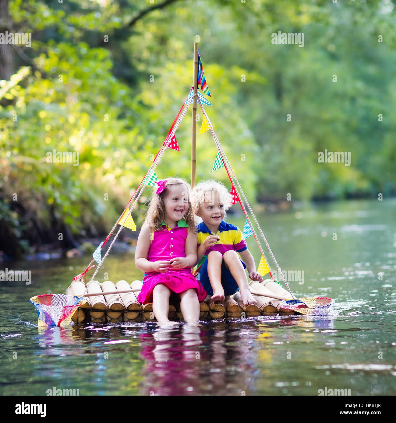 Two children on wooden raft catching fish with a colorful net in a ...