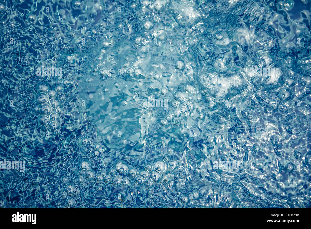 blue toned whirling water background with bubbles and ripples in ...