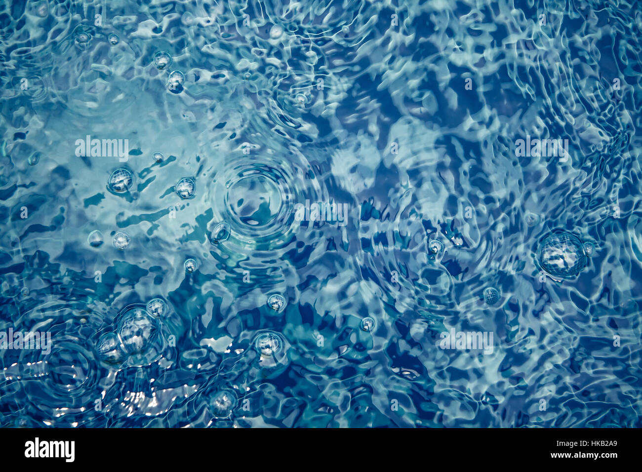 whirling water background with bubbles and ripples in swimming pool in ...