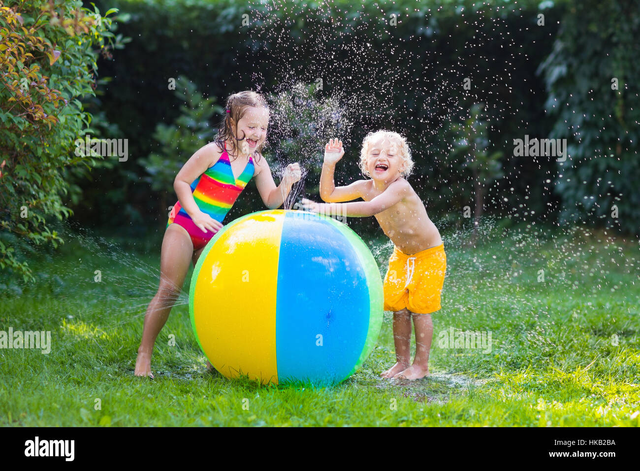 Child playing with toy ball garden sprinkler. Preschooler kid run and ...
