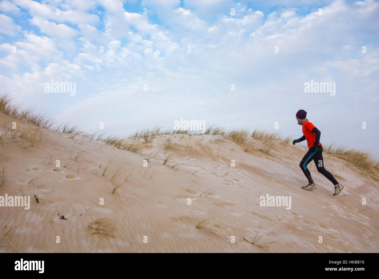 Mature man running on sand dunes covered in frost at Seaton Carew on ...