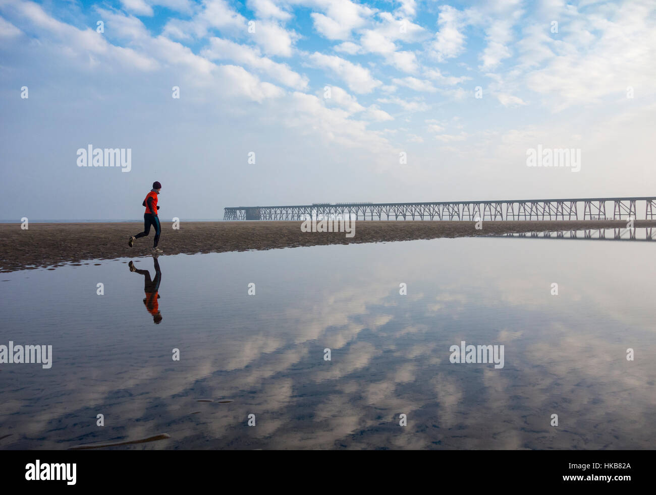 Man jogging, running on beach near Steetley pier at sunrise. Hartlepool ...