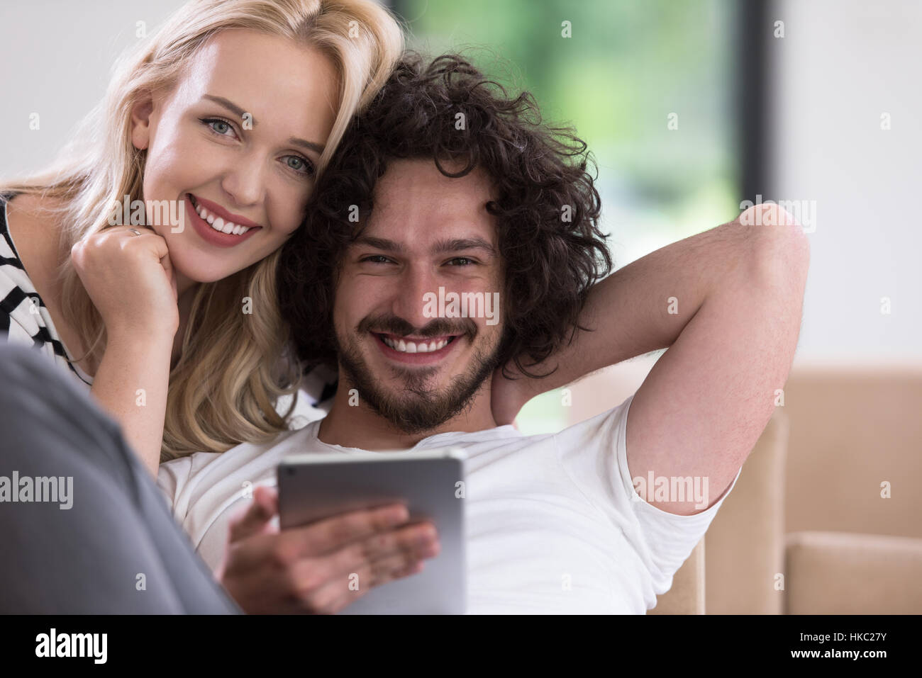 Young couple relaxing at luxurious home with tablet computers reading ...