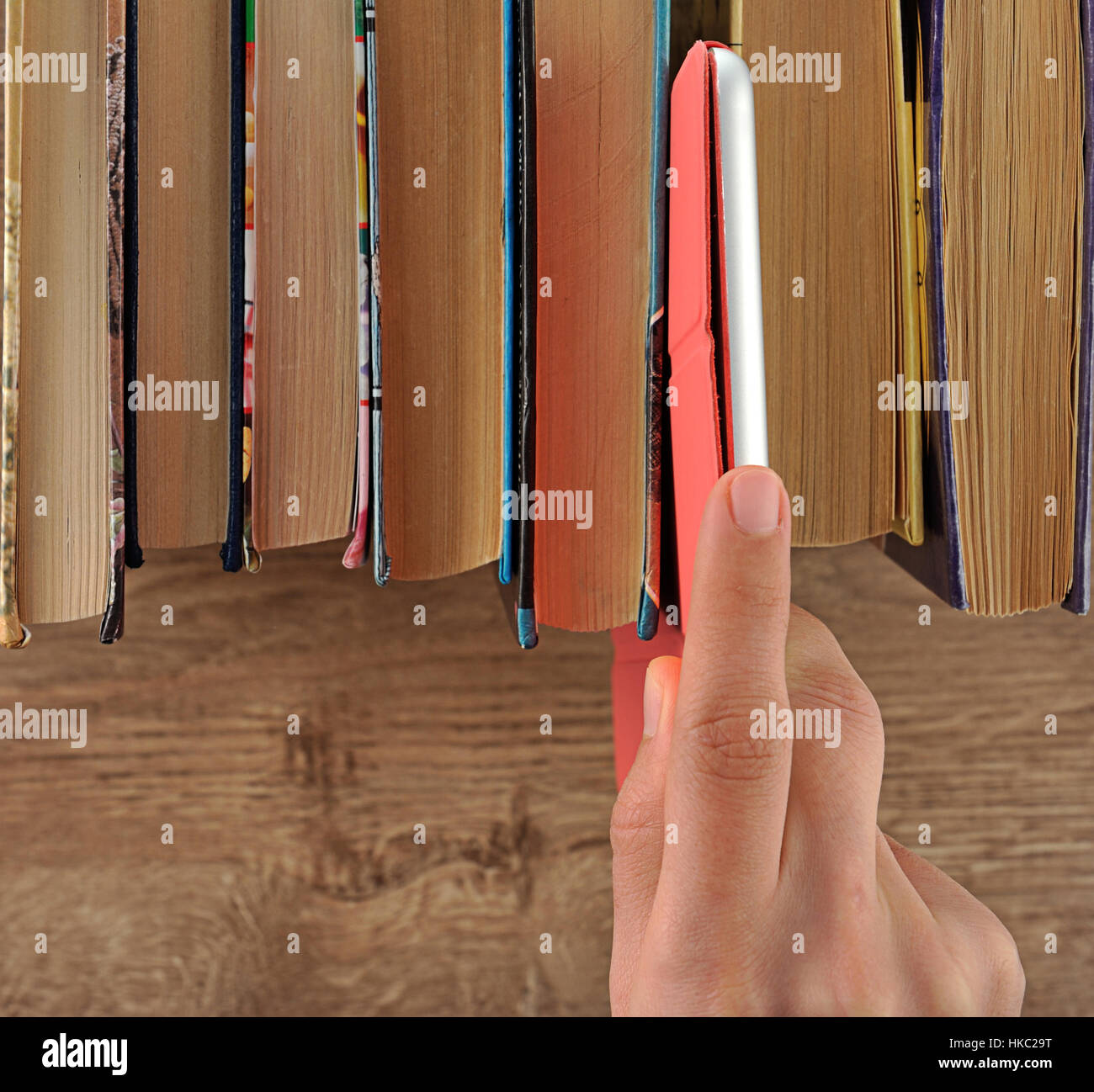 Hand taking tablet from bookshelf Stock Photo - Alamy