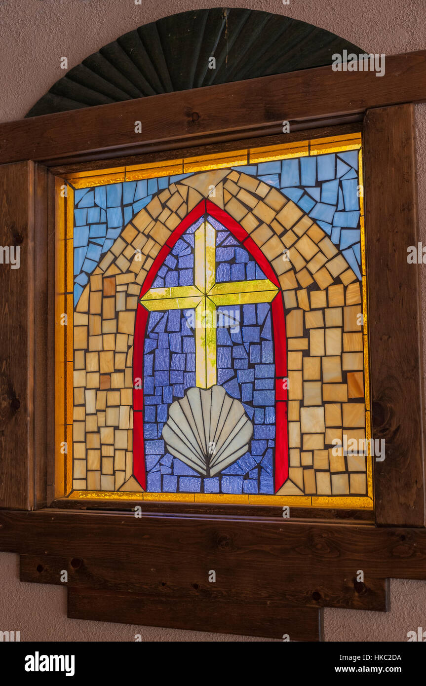 A religious themed stained glass window with a cross and a sea shell in ...