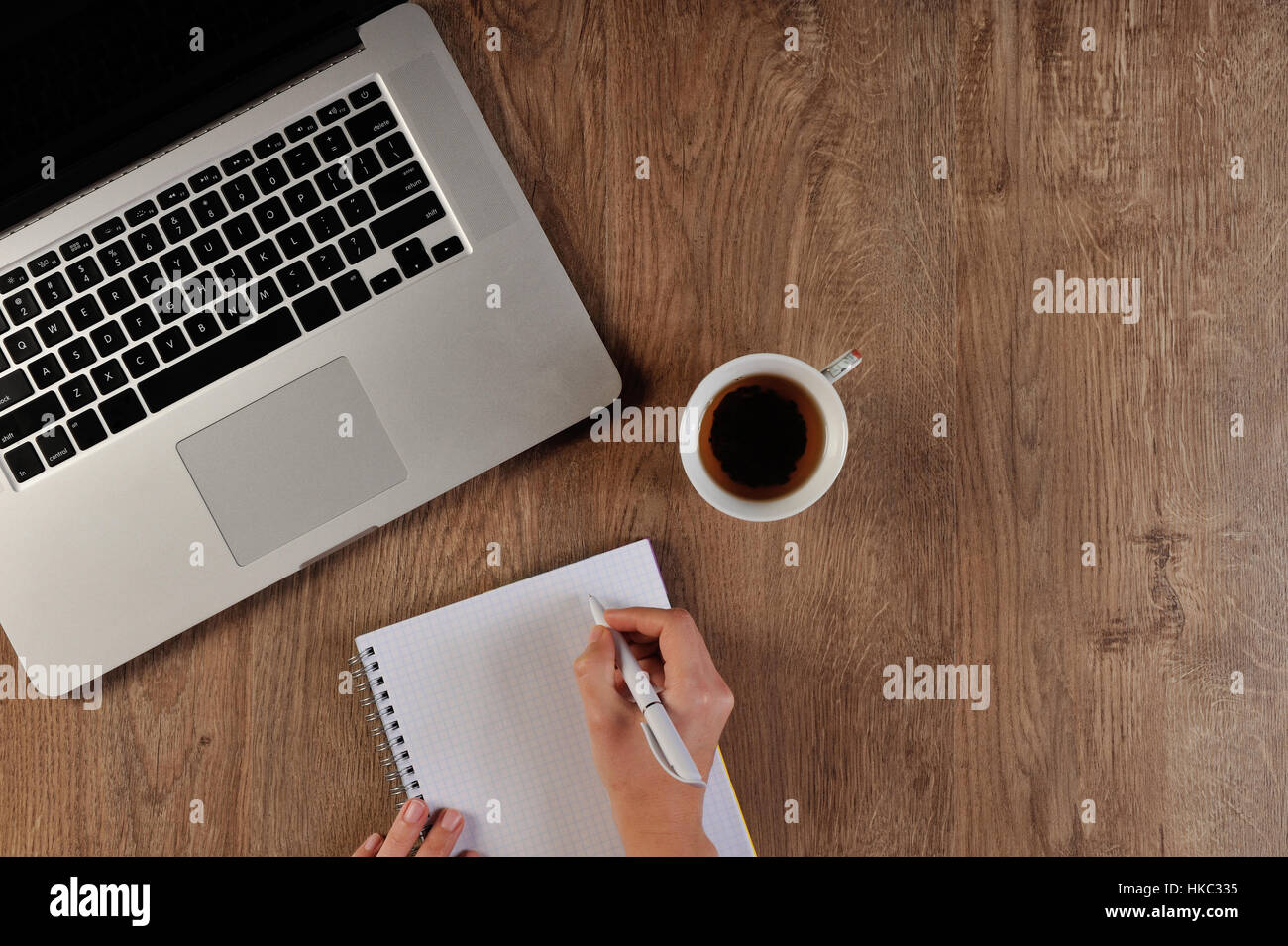 person writing in notebook infront of laptop Stock Photo - Alamy