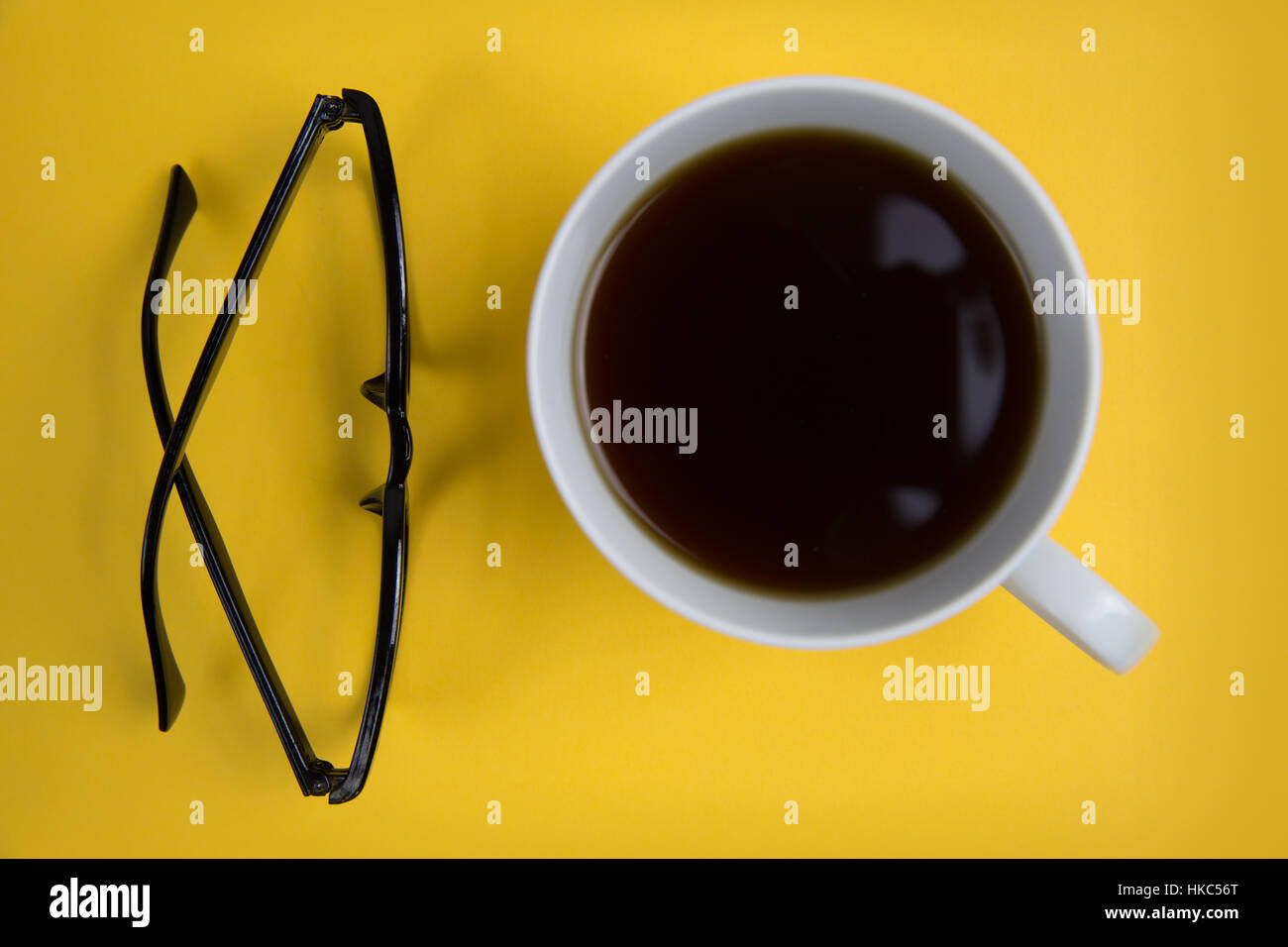 Coffee cup and glasses overhead on bright yellow background Stock Photo ...