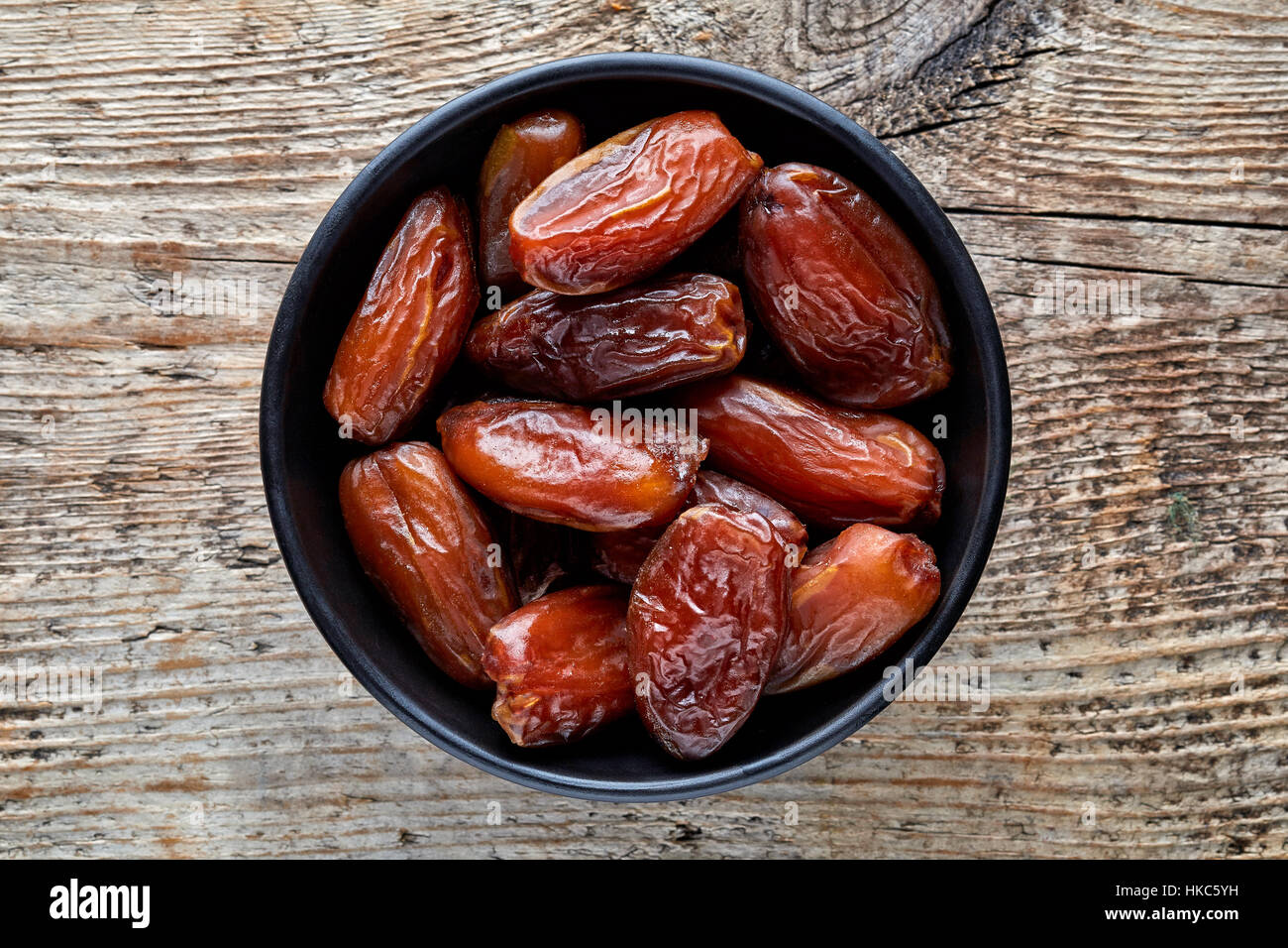 Bowl of pitted dates on wooden background, top view Stock Photo - Alamy
