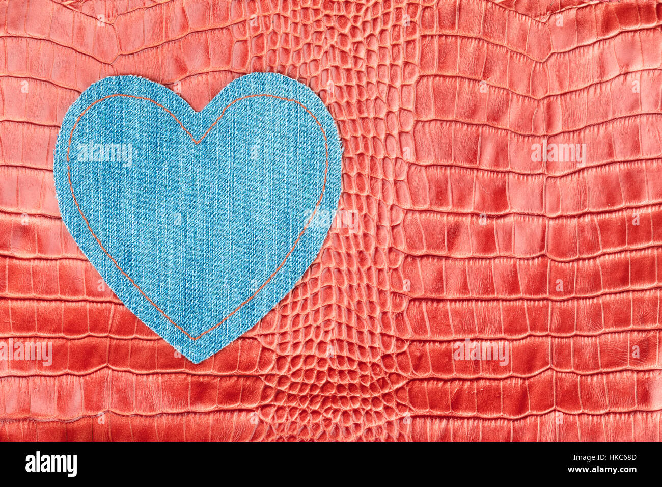 Heart made of denim, lies on the red crocodile skin. View from above ...