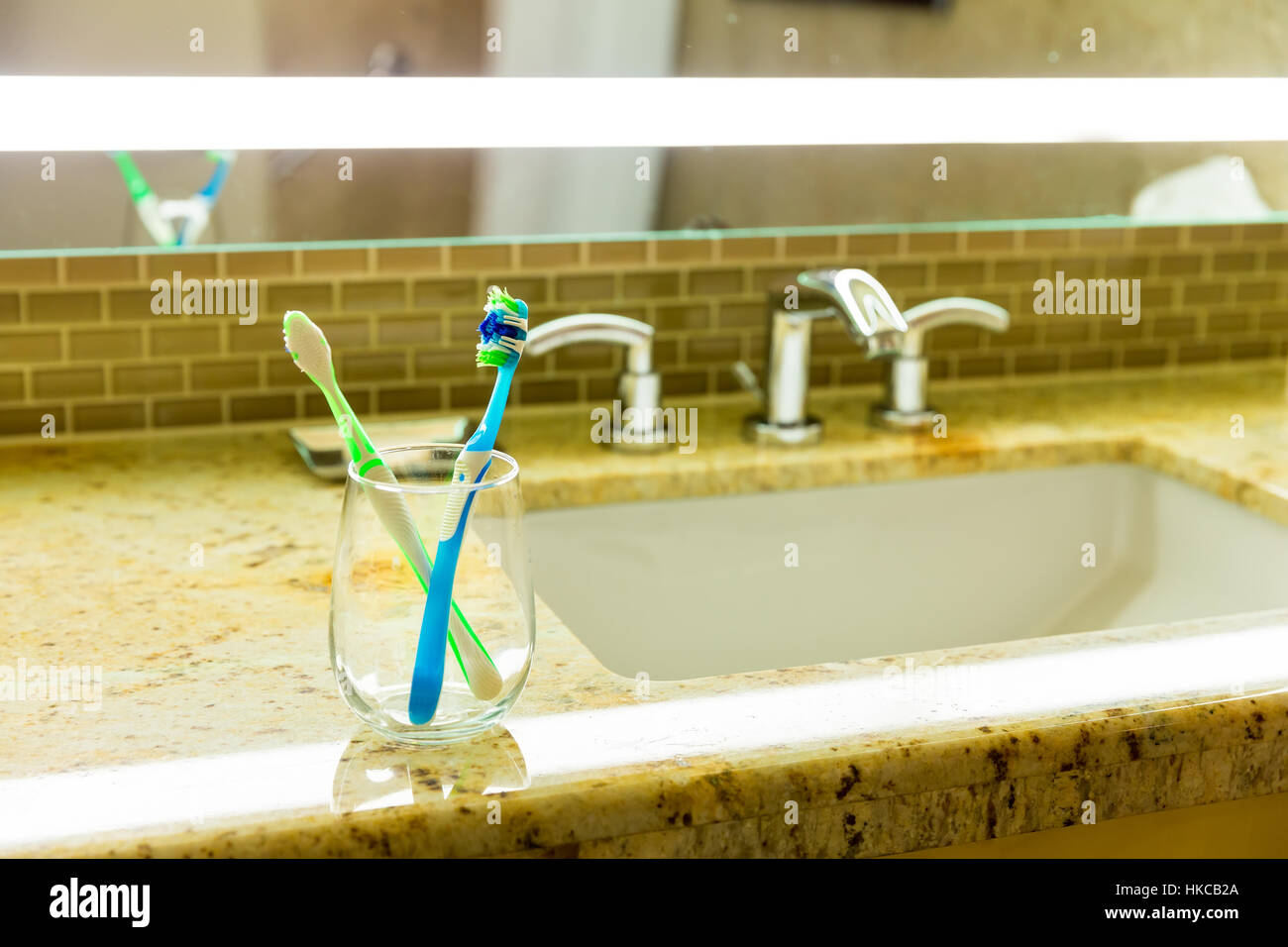Toothbrushes in a glass on counter Stock Photo - Alamy