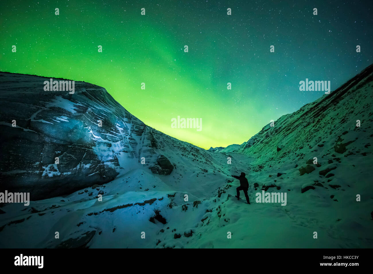 A man lights up the ice of Castner Glacier with a flashlight underneath ...