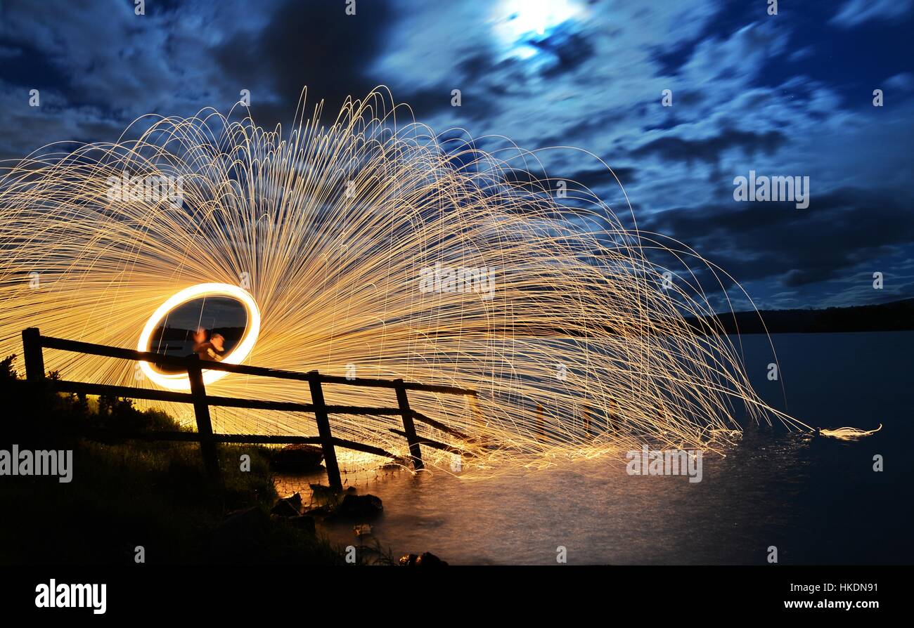 A long exposure of steel wool spinning on a with sparks reflected in a ...