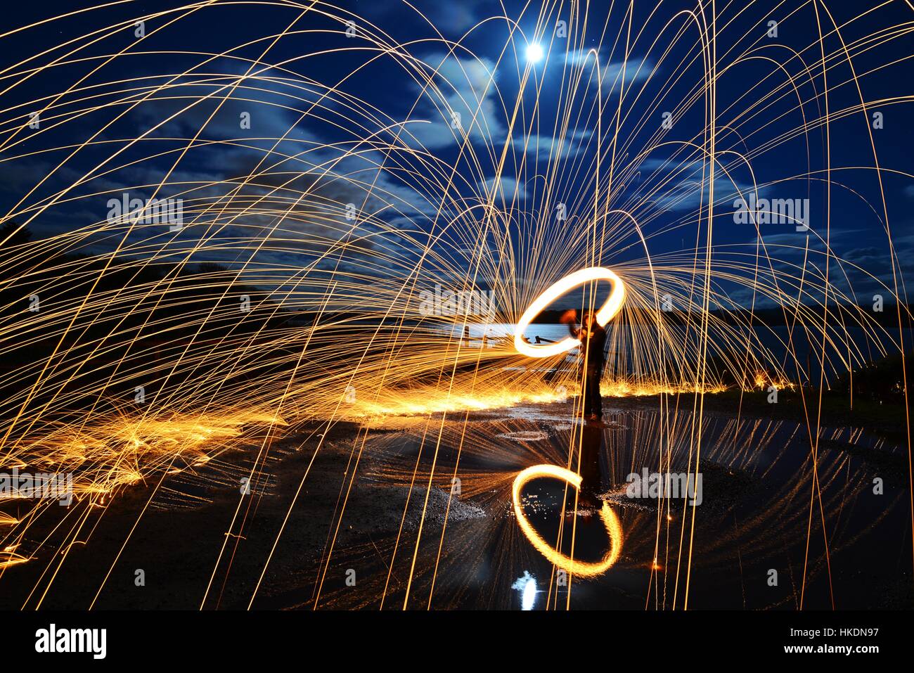 A long exposure of steel wool spinning on a with sparks reflected in a ...