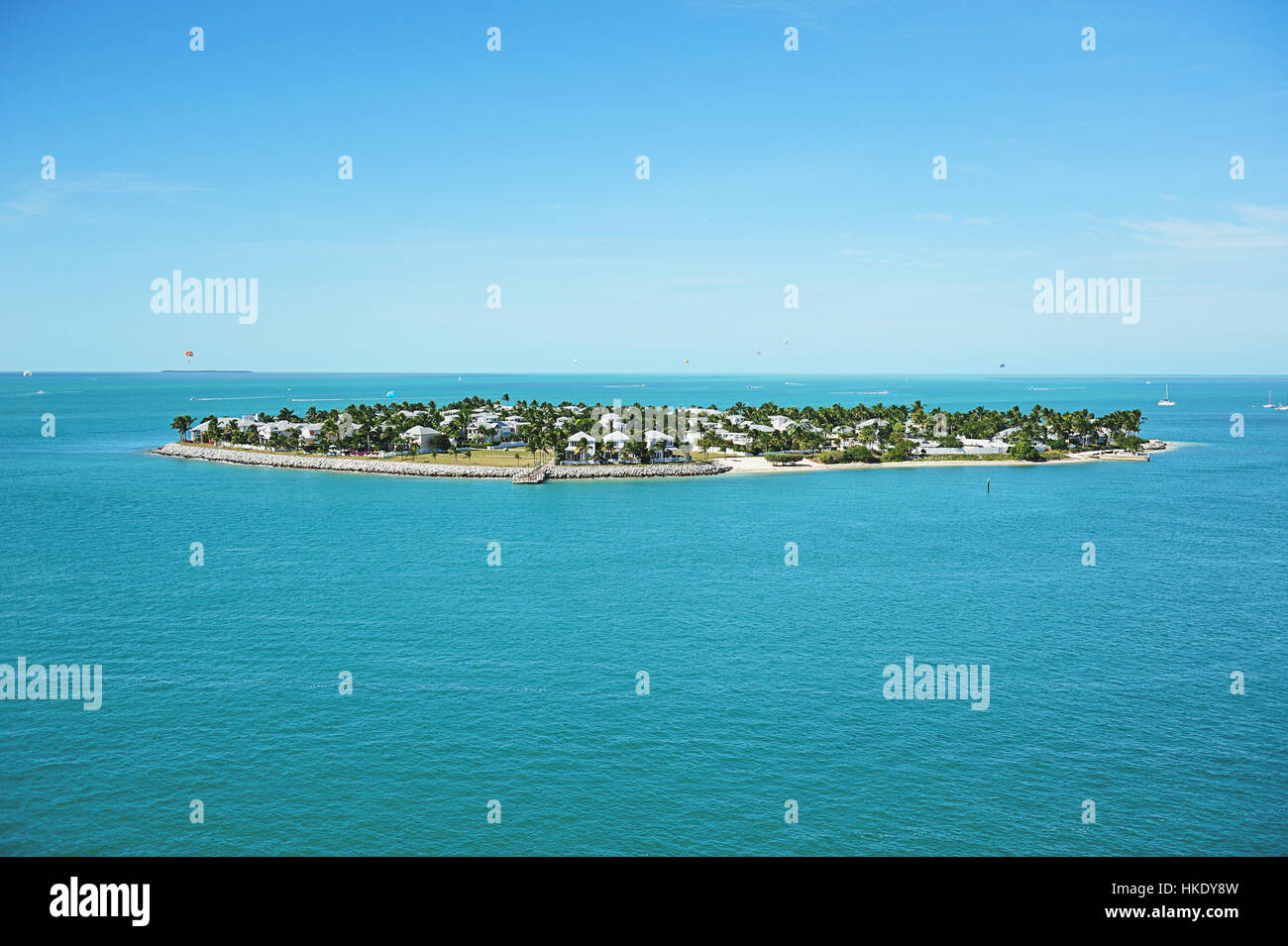 Round island in blue water with parasail around Stock Photo - Alamy