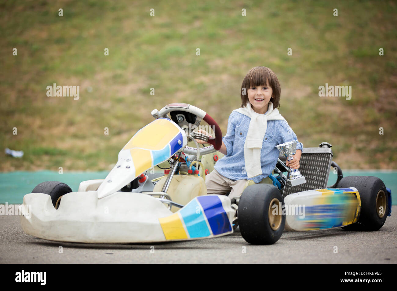 Cute child, riding go cart, wins champion cup, happiness winner concept ...