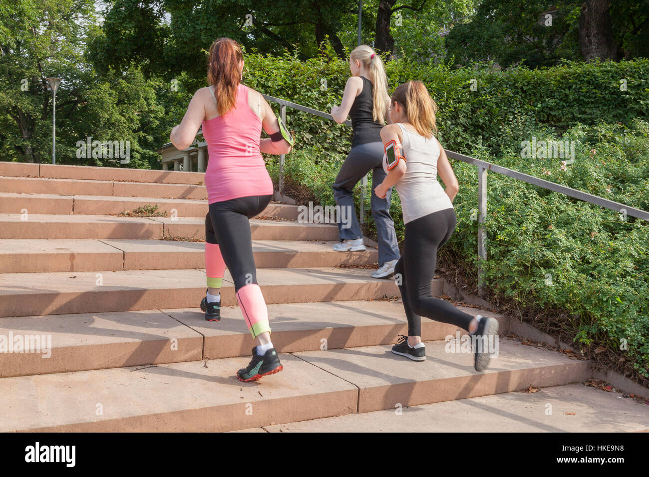 three athletes running up the stairs with cityscape panorama in the ...