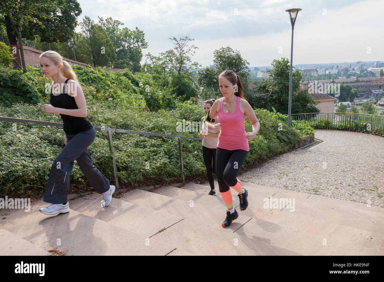 three athletes running up the stairs with cityscape panorama in the ...