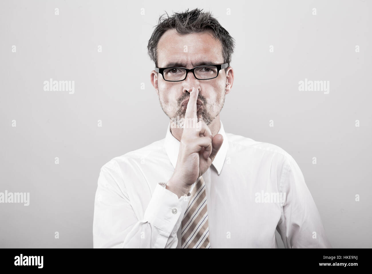 Man makes gesture with his finger to be silent Stock Photo - Alamy