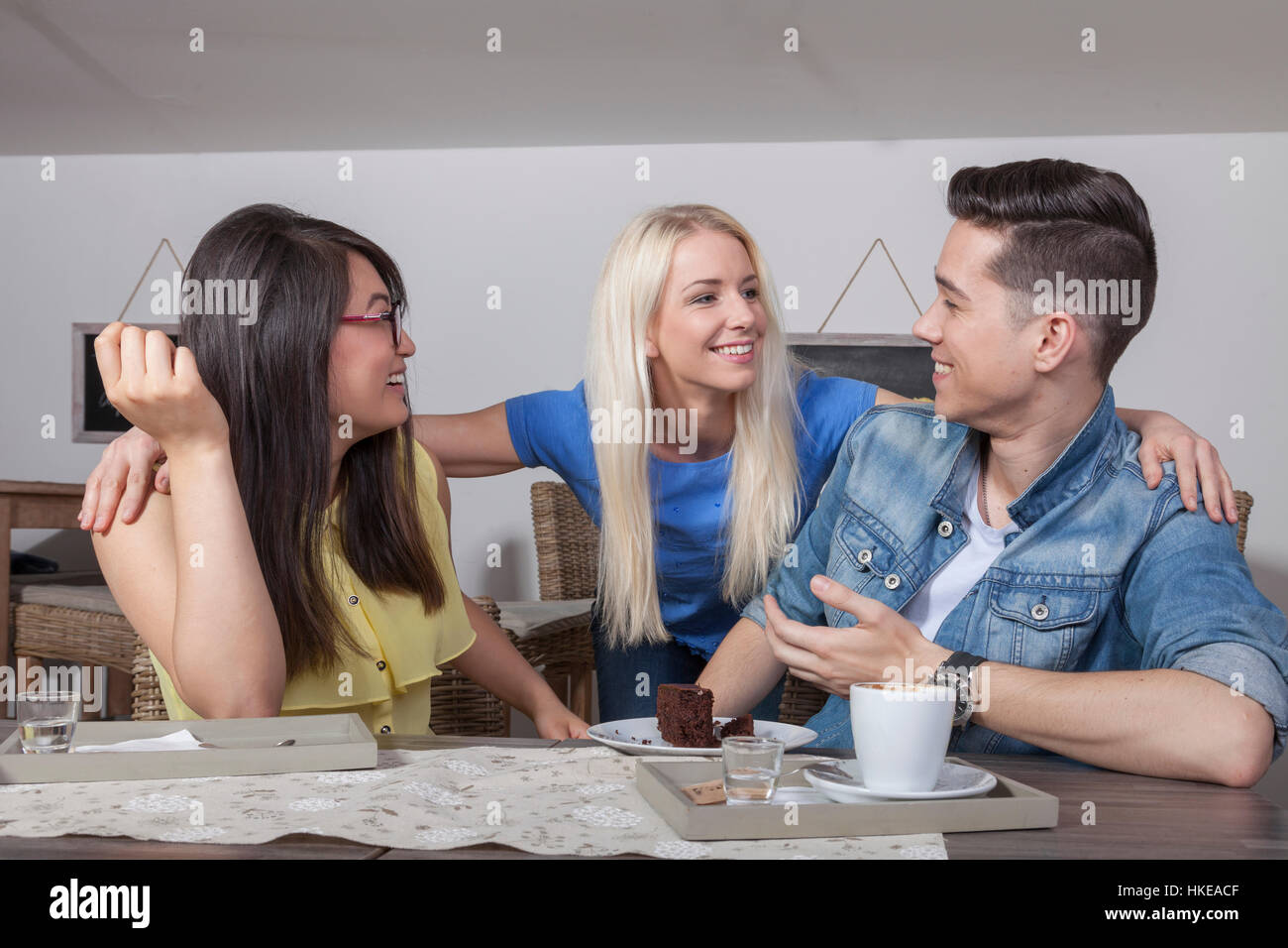 Three friends in cafeteria environment Stock Photo - Alamy