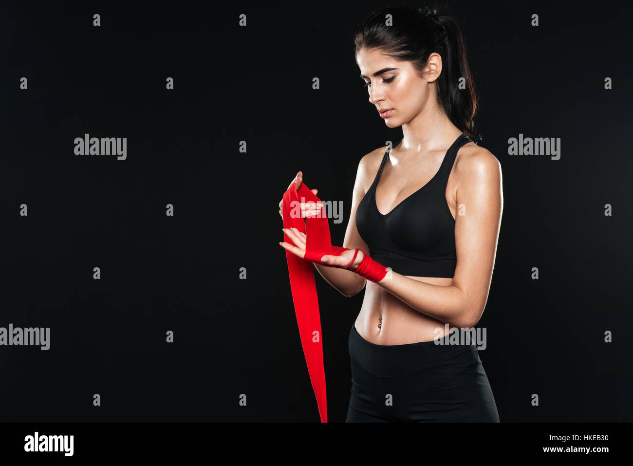 Portrait of confident female fighter tying bandage on hand against ...